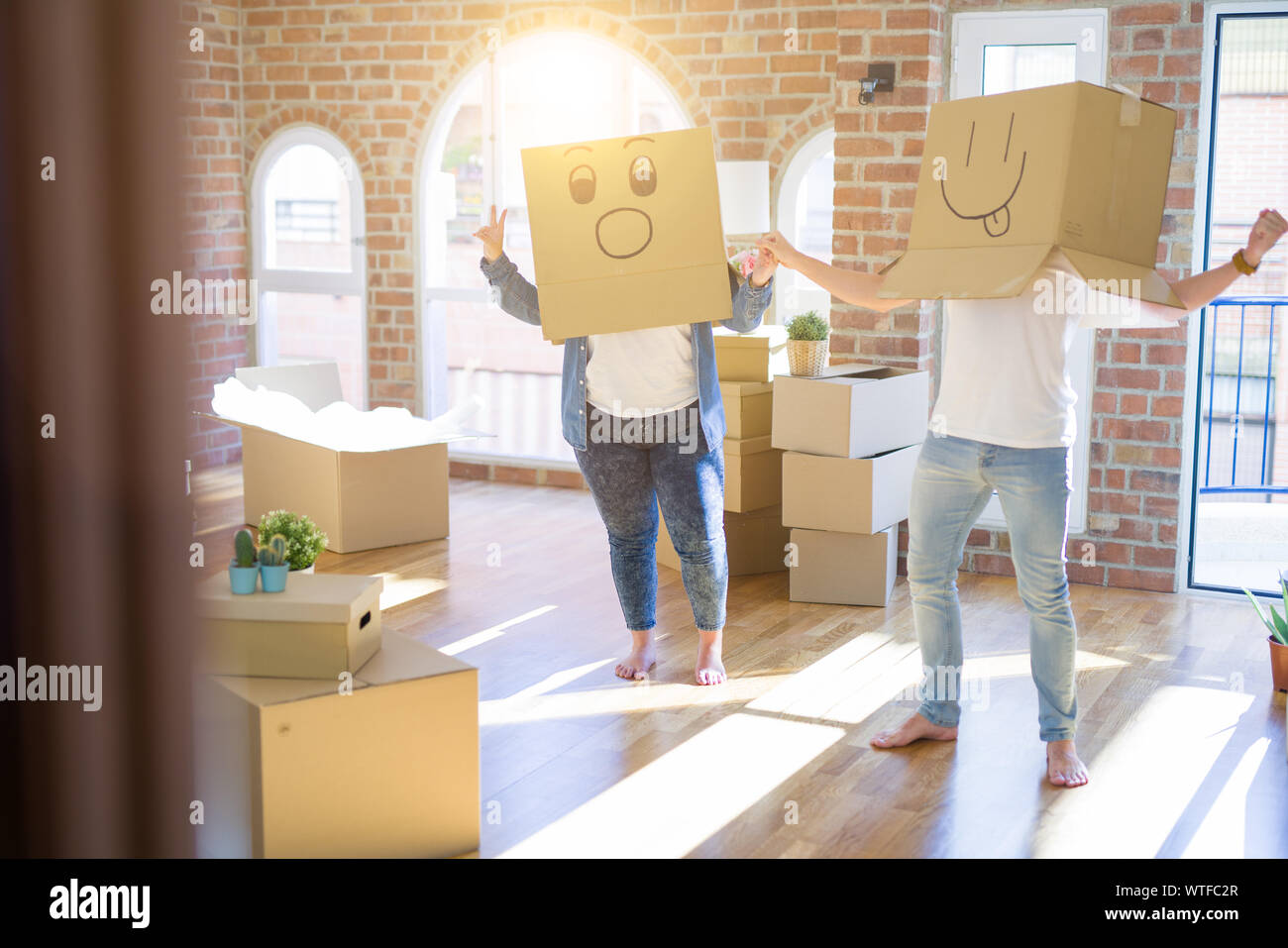 Crazy couple wearing cardboard boxes with funny emoji faces over head ...