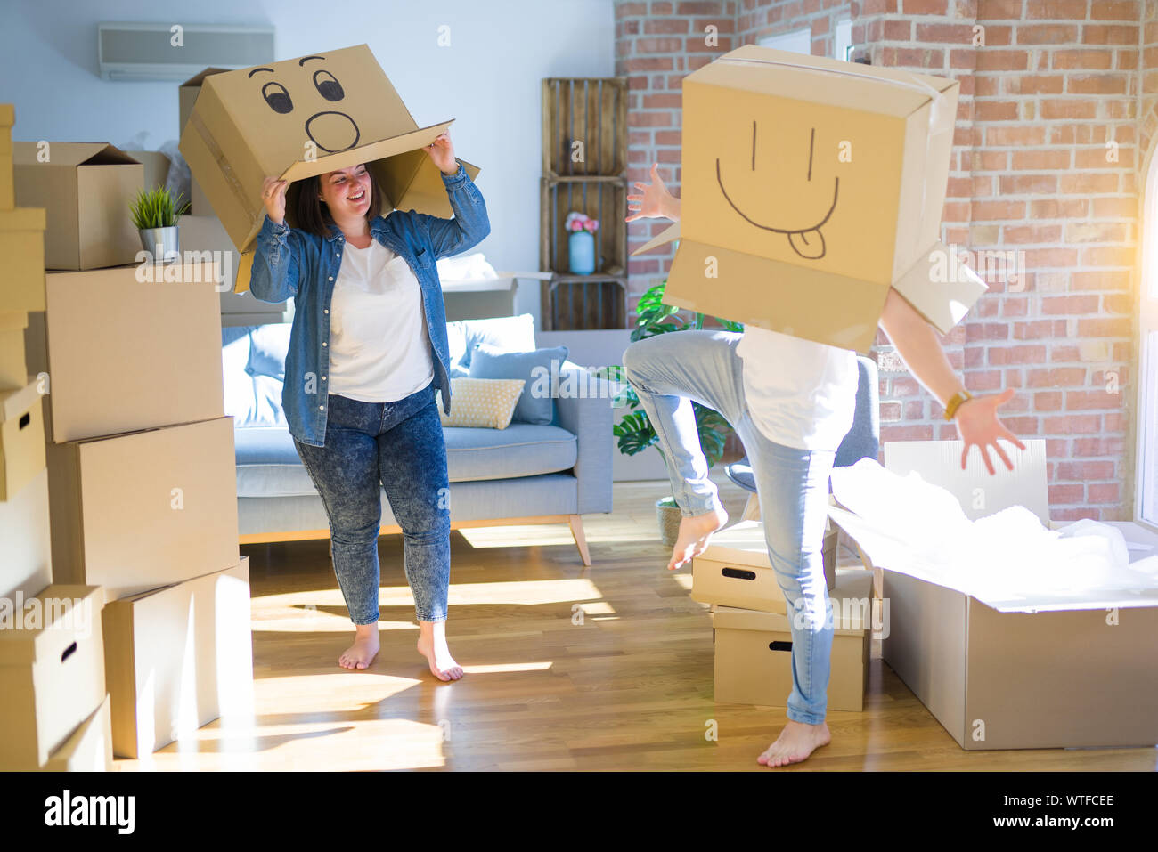 Crazy couple wearing cardboard boxes with funny emoji faces over head ...