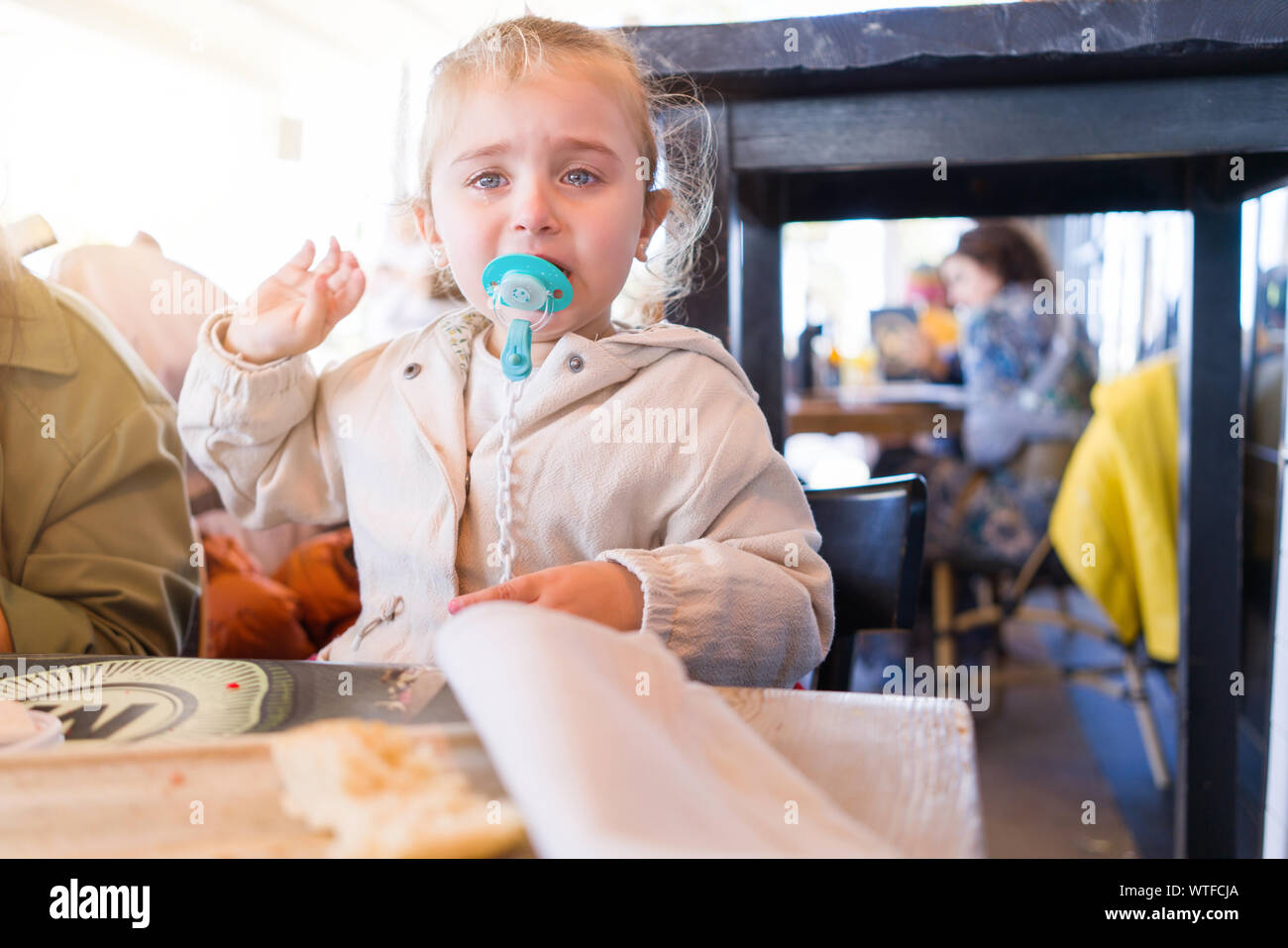 Beautiful toddler child girl sitting on baby highchair crying using ...
