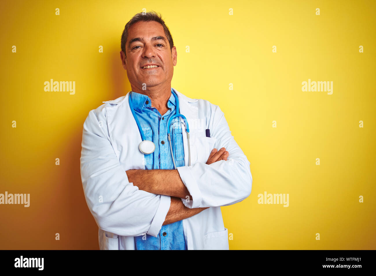Handsome middle age doctor man wearing stethoscope over isolated yellow ...