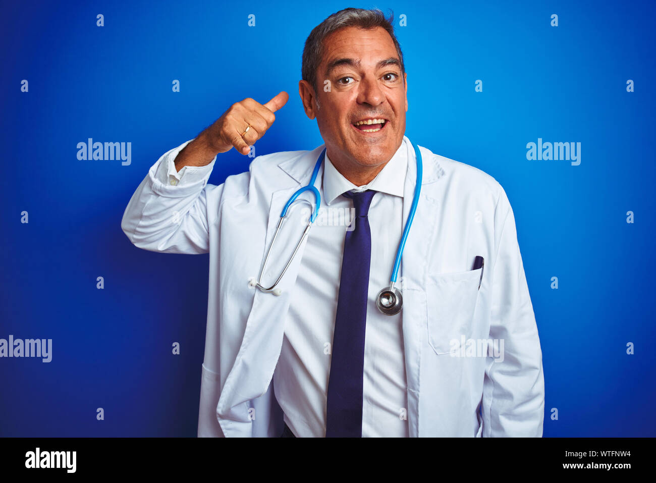 Handsome middle age doctor man wearing stethoscope over isolated blue ...