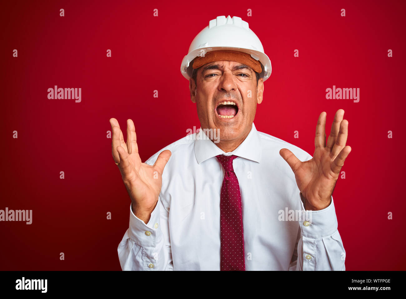 Handsome middle age engineer man wearing security helmet over isolated ...