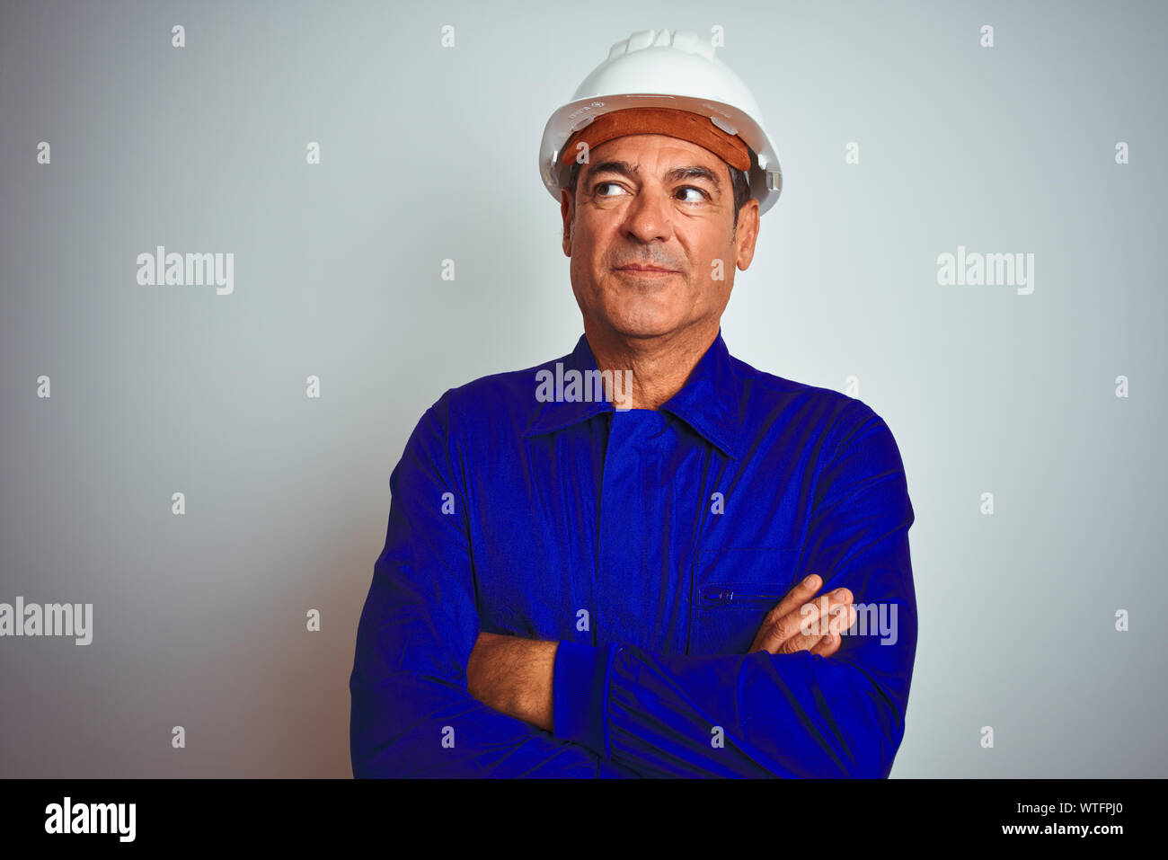 Handsome middle age worker man wearing uniform and helmet over isolated ...