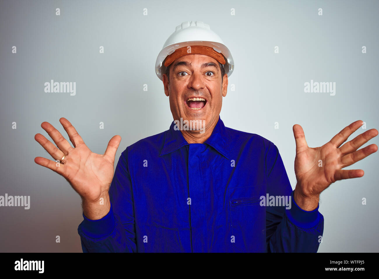 Handsome middle age worker man wearing uniform and helmet over isolated ...