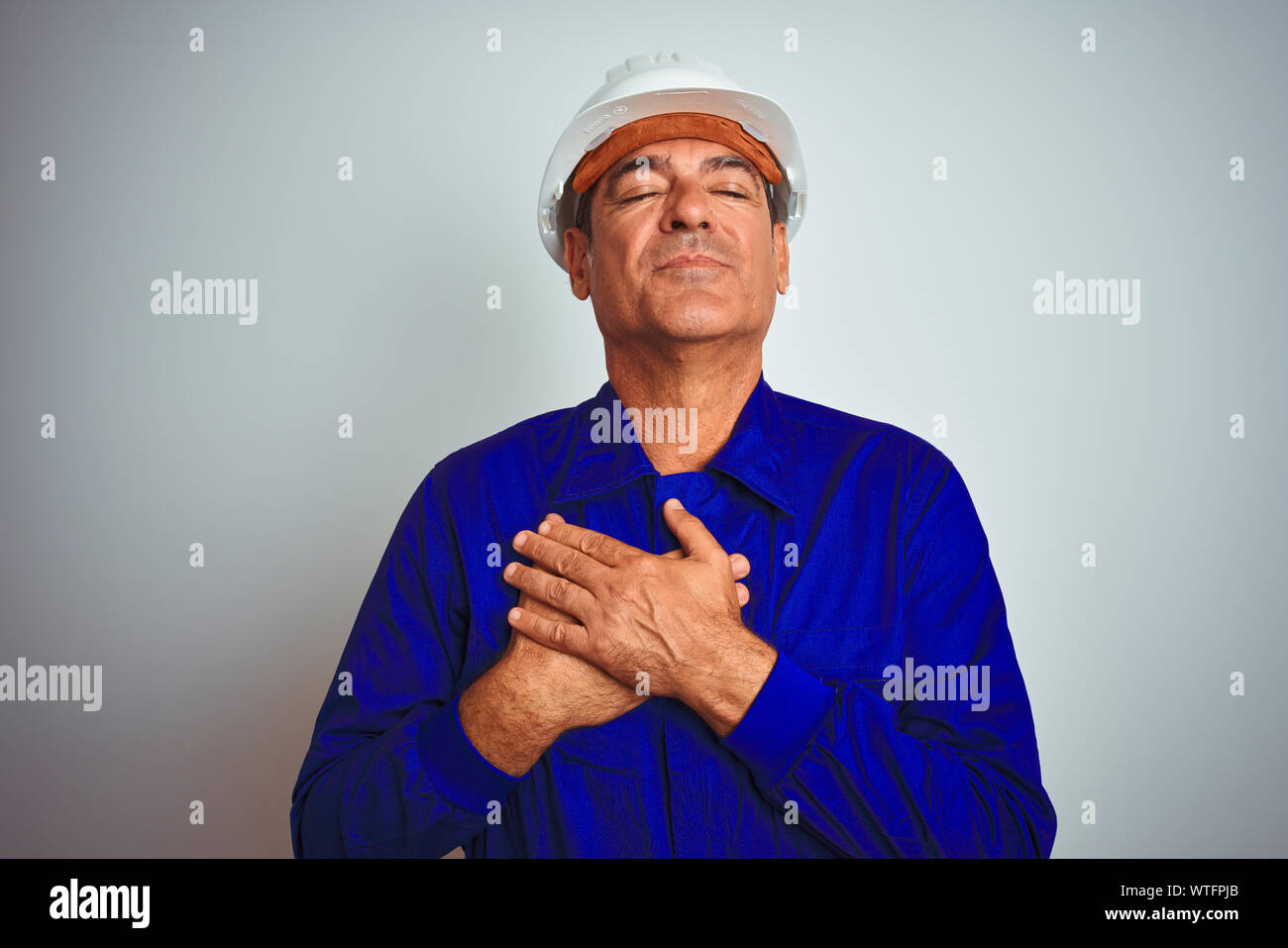 Handsome middle age worker man wearing uniform and helmet over isolated ...