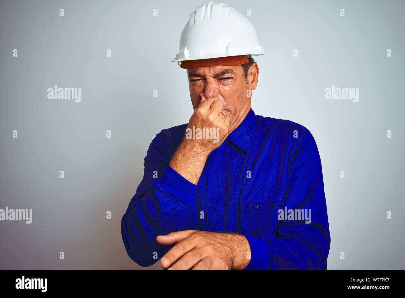Handsome middle age worker man wearing uniform and helmet over isolated ...
