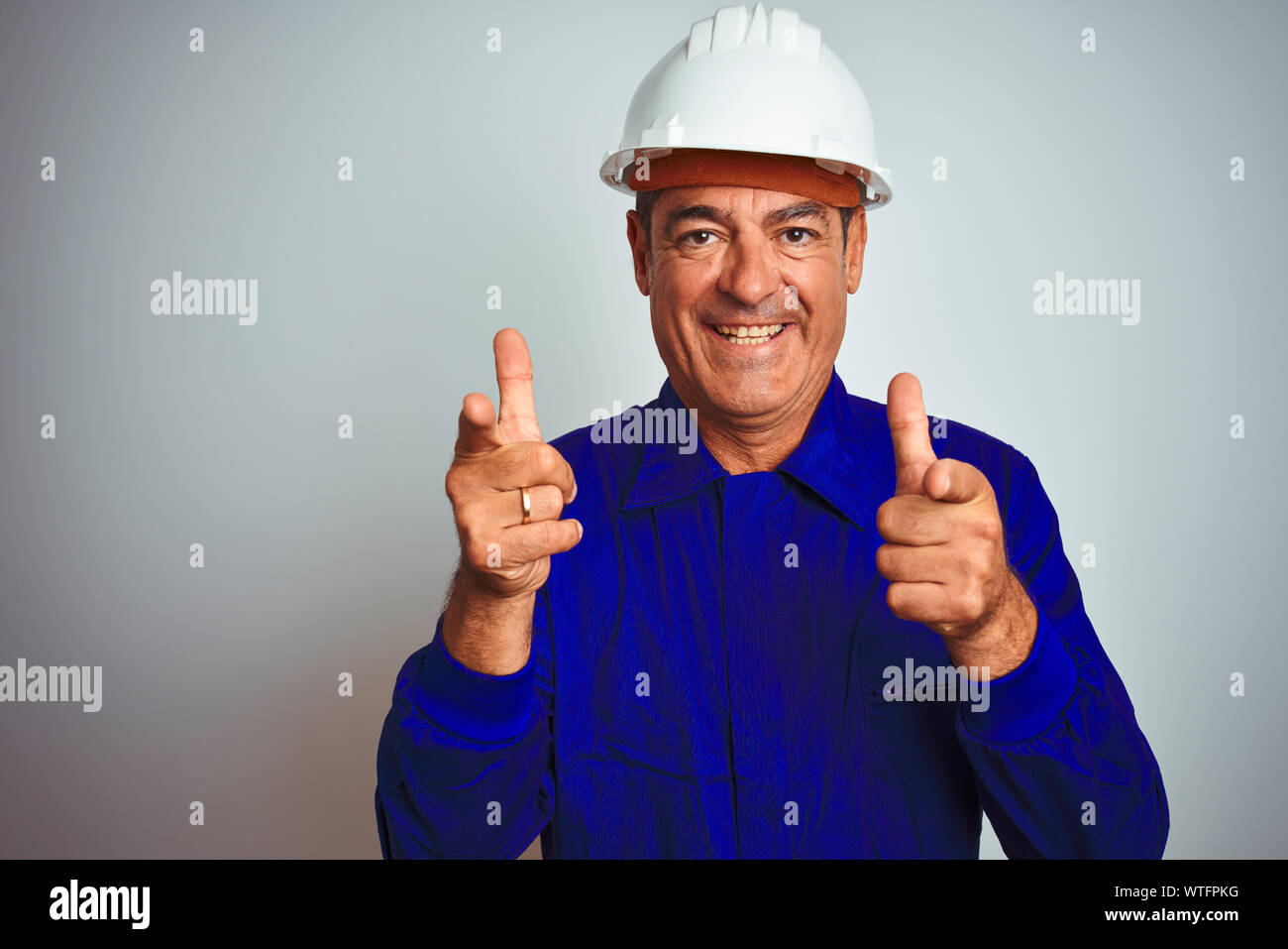 Handsome middle age worker man wearing uniform and helmet over isolated ...