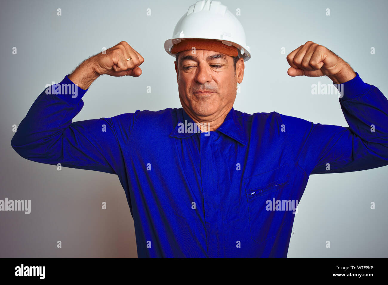 Handsome middle age worker man wearing uniform and helmet over isolated ...