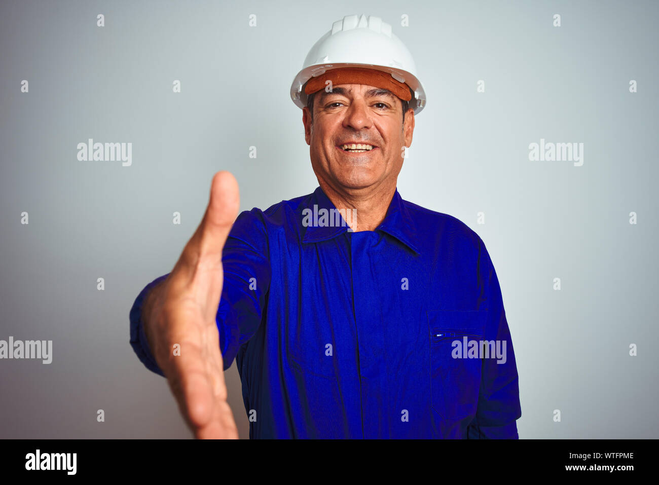 Handsome middle age worker man wearing uniform and helmet over isolated ...