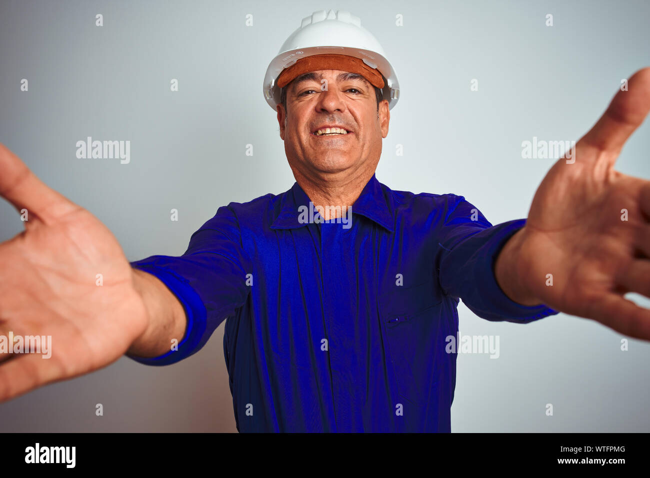 Handsome middle age worker man wearing uniform and helmet over isolated ...
