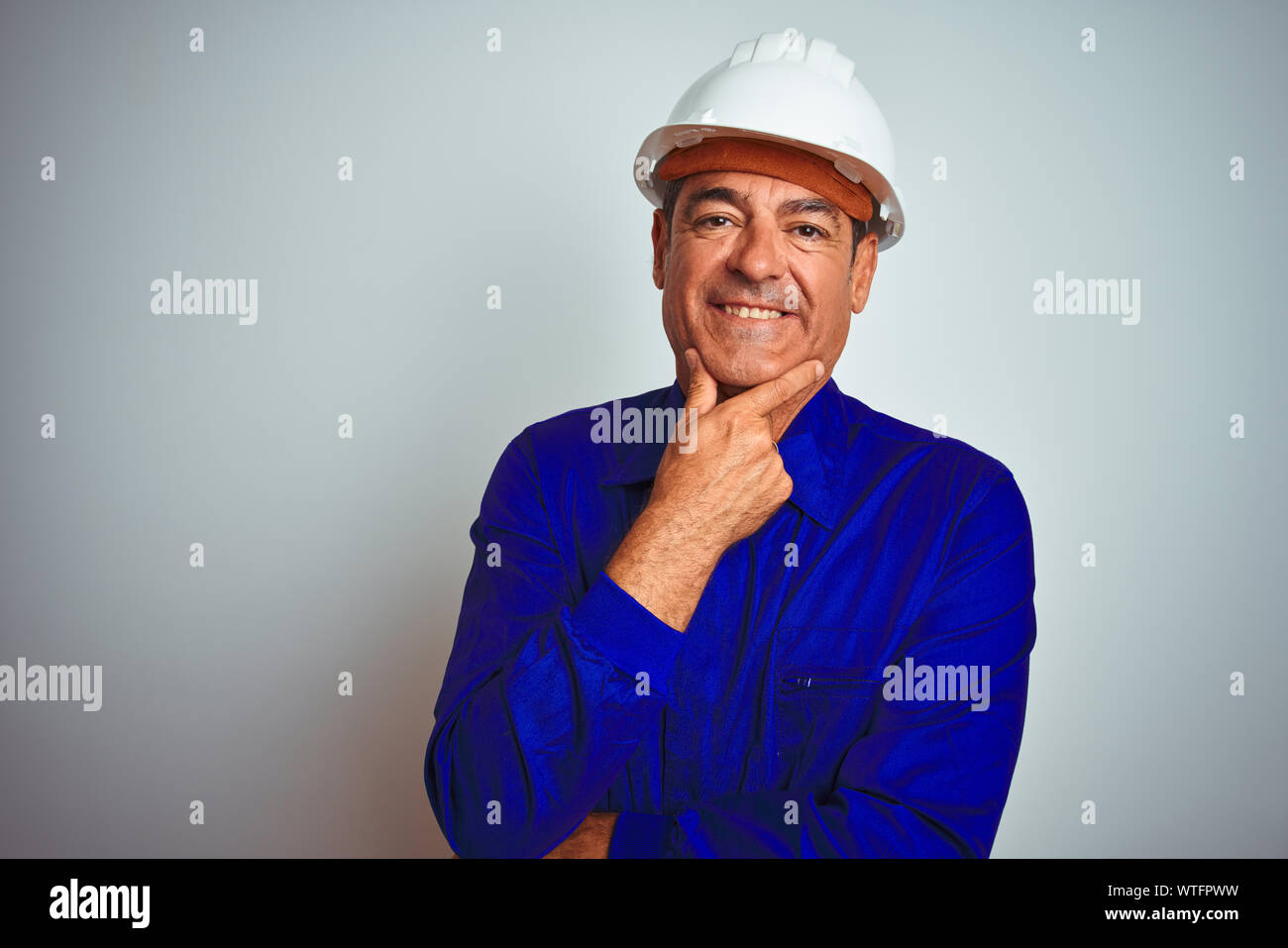 Handsome middle age worker man wearing uniform and helmet over isolated ...