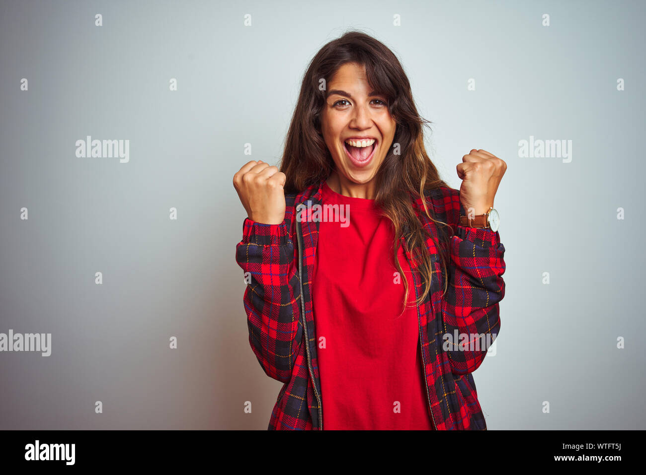 Young beautiful woman wearing red t-shirt and jacket standing over ...