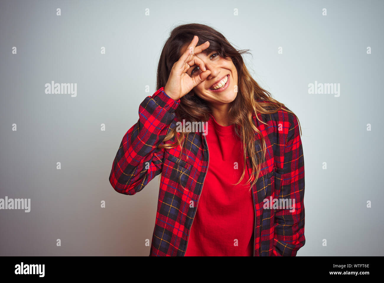 Young beautiful woman wearing red t-shirt and jacket standing over ...