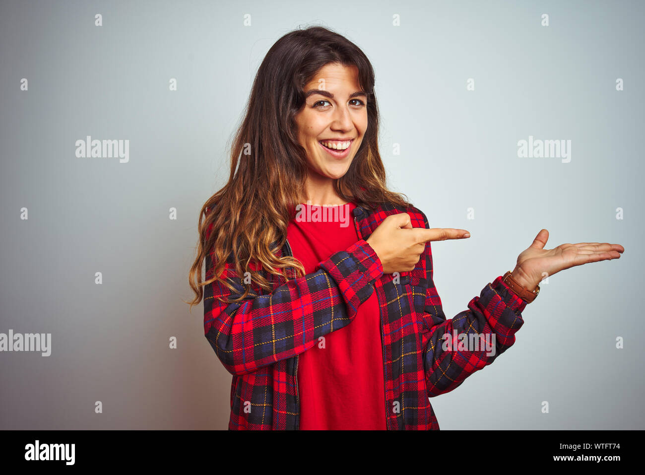 Young beautiful woman wearing red t-shirt and jacket standing over ...