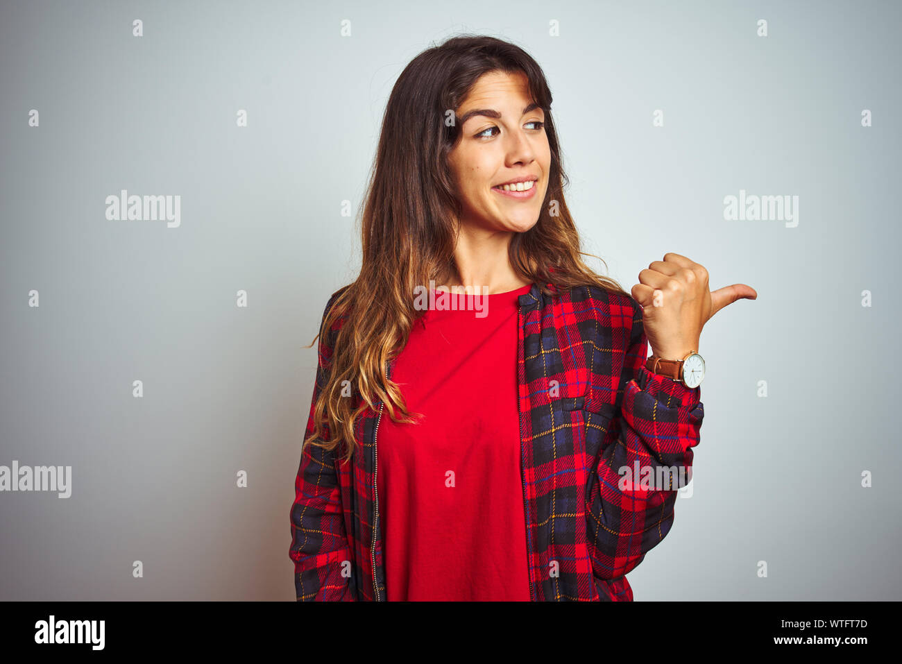 Young beautiful woman wearing red t-shirt and jacket standing over ...