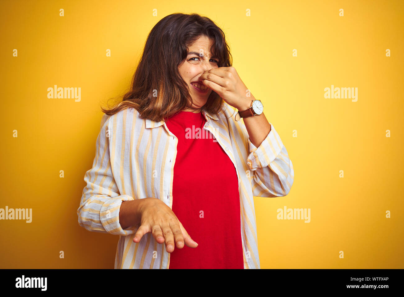 Young beautiful woman wearing red t-shirt and stripes shirt over yellow ...
