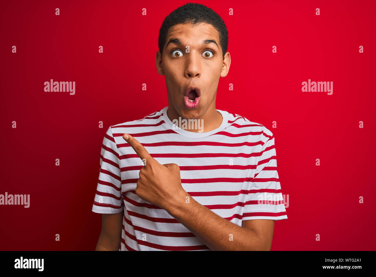 Young Handsome Arab Man Wearing Striped T Shirt Over Isolated Red