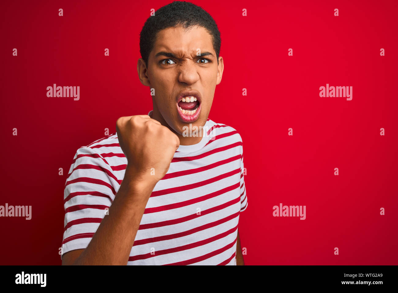 Young Handsome Arab Man Wearing Striped T Shirt Over Isolated Red