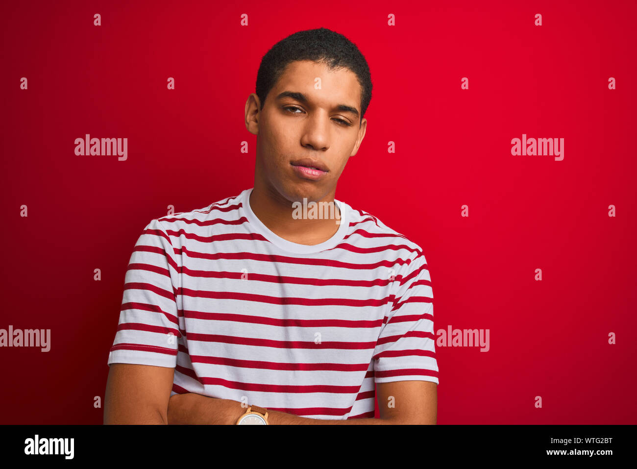Young handsome arab man wearing striped t-shirt over isolated red ...