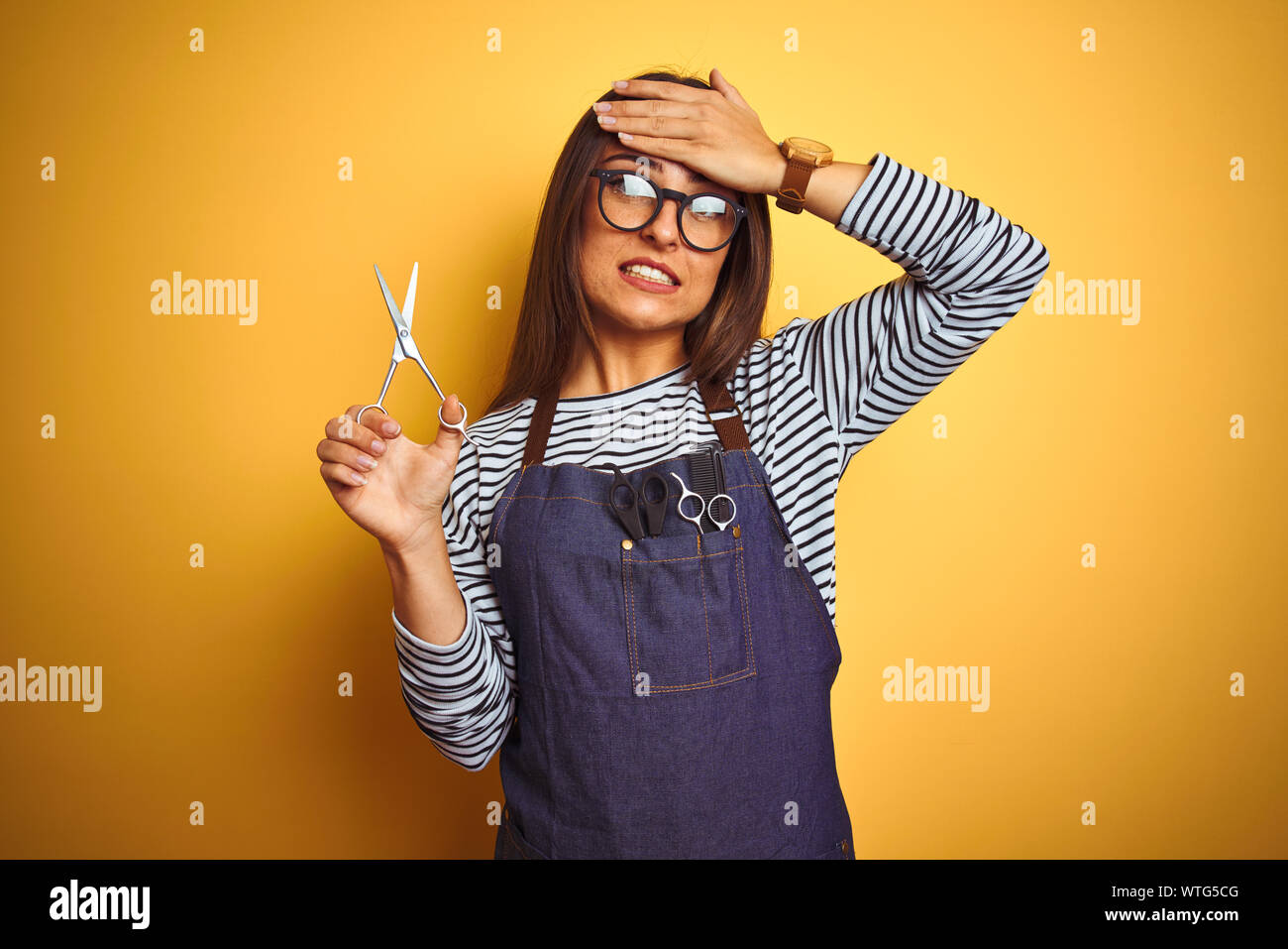 Young beautiful hairdresser woman holding scissors standing over ...