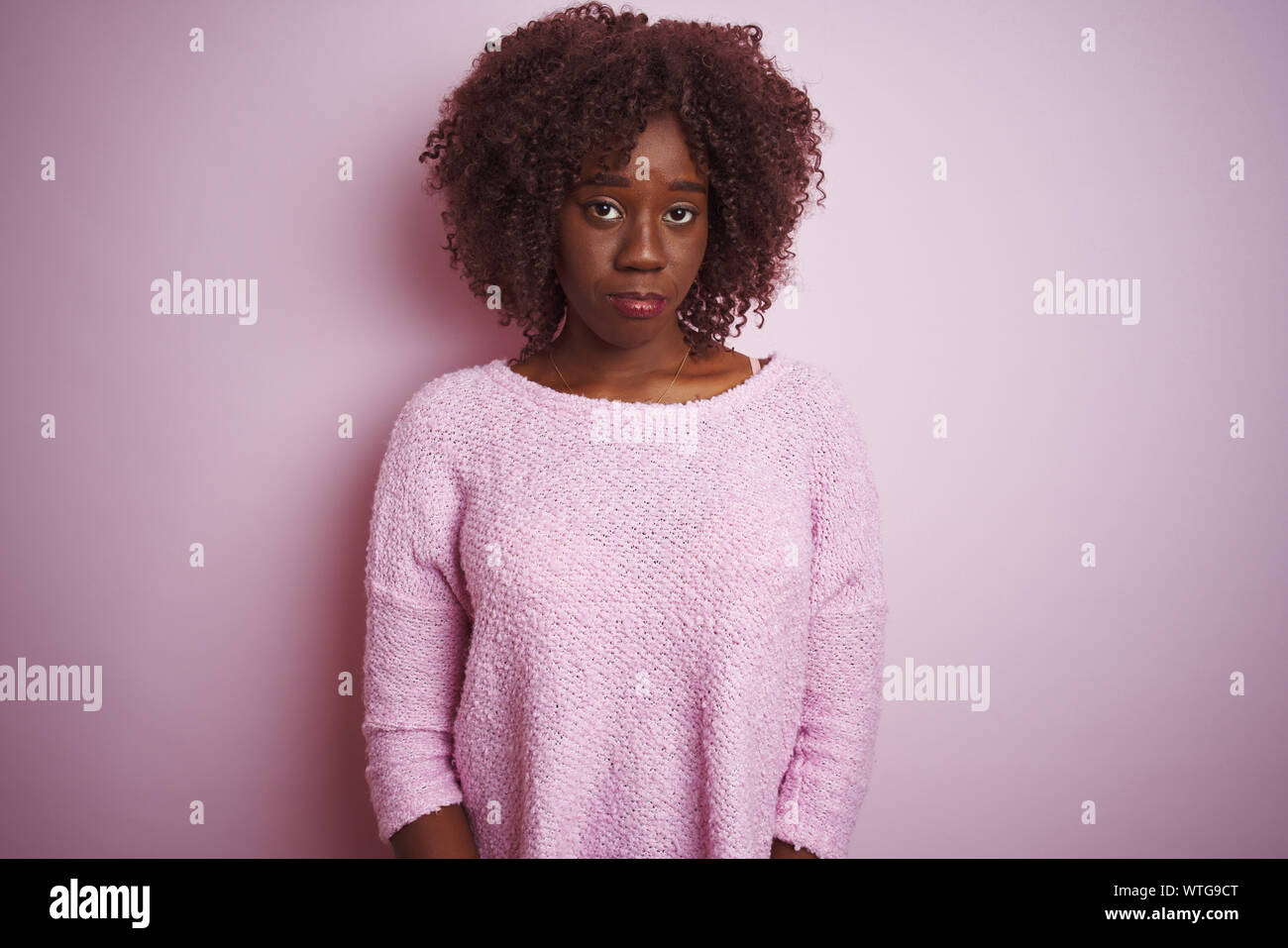 Young african afro woman wearing sweater standing over isolated pink ...