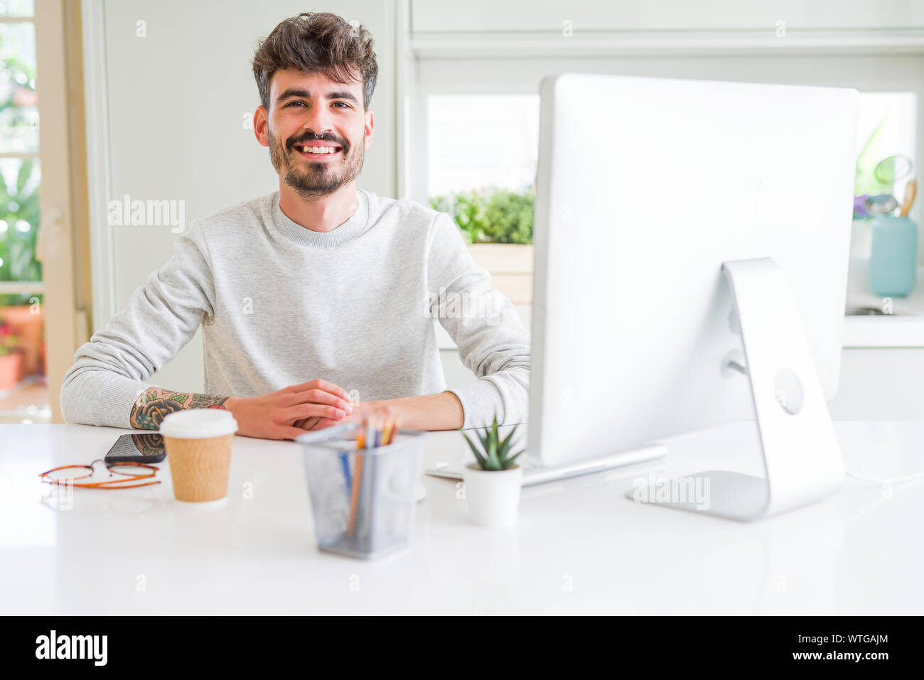 Young man working using computer with a happy and cool smile on face ...