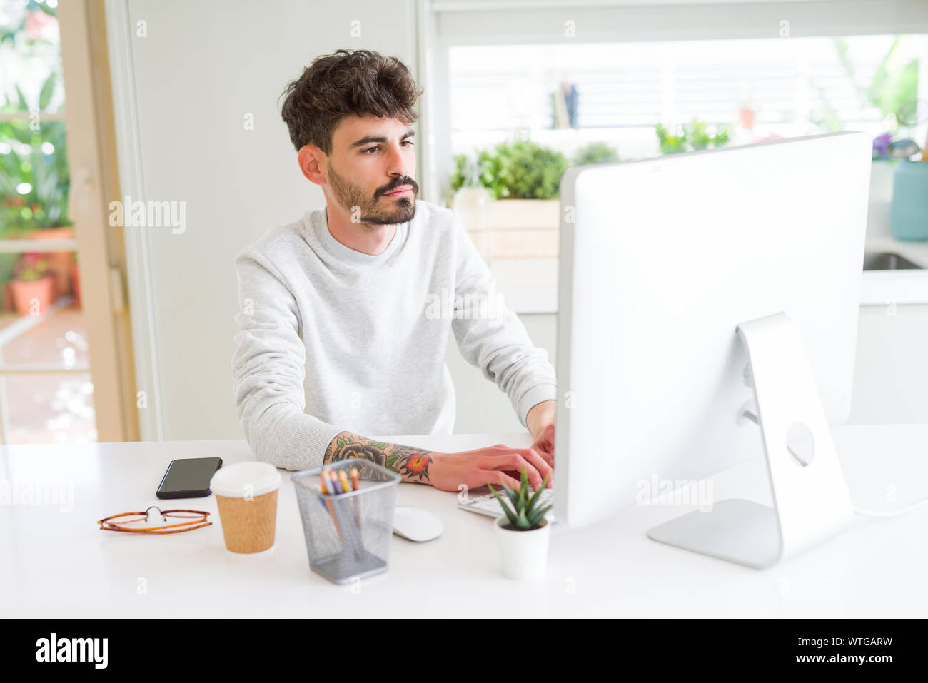 Young handsome man working using computer, smiling concentrated on ...