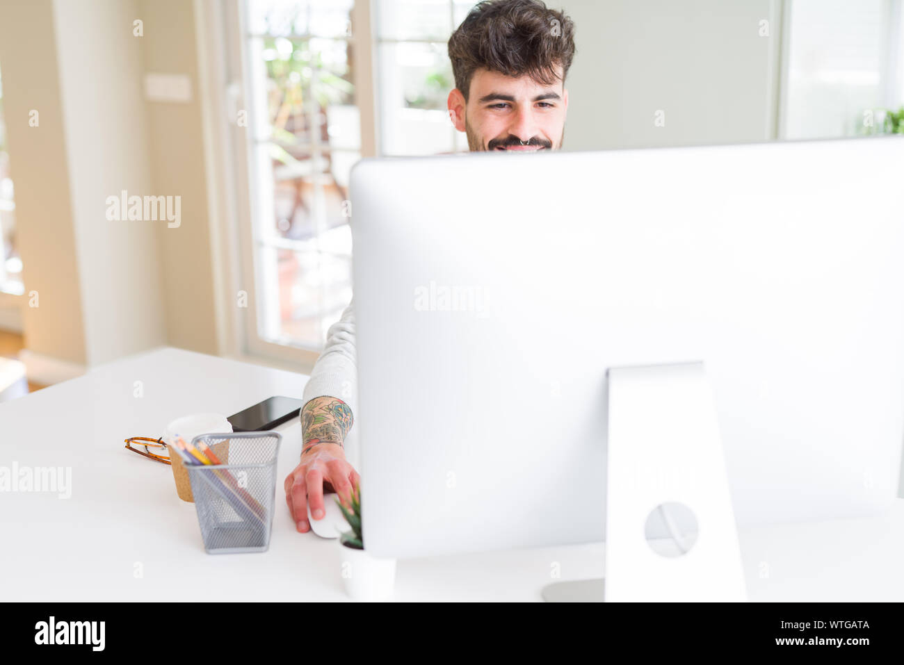 Young handsome man working using computer, smiling concentrated on ...