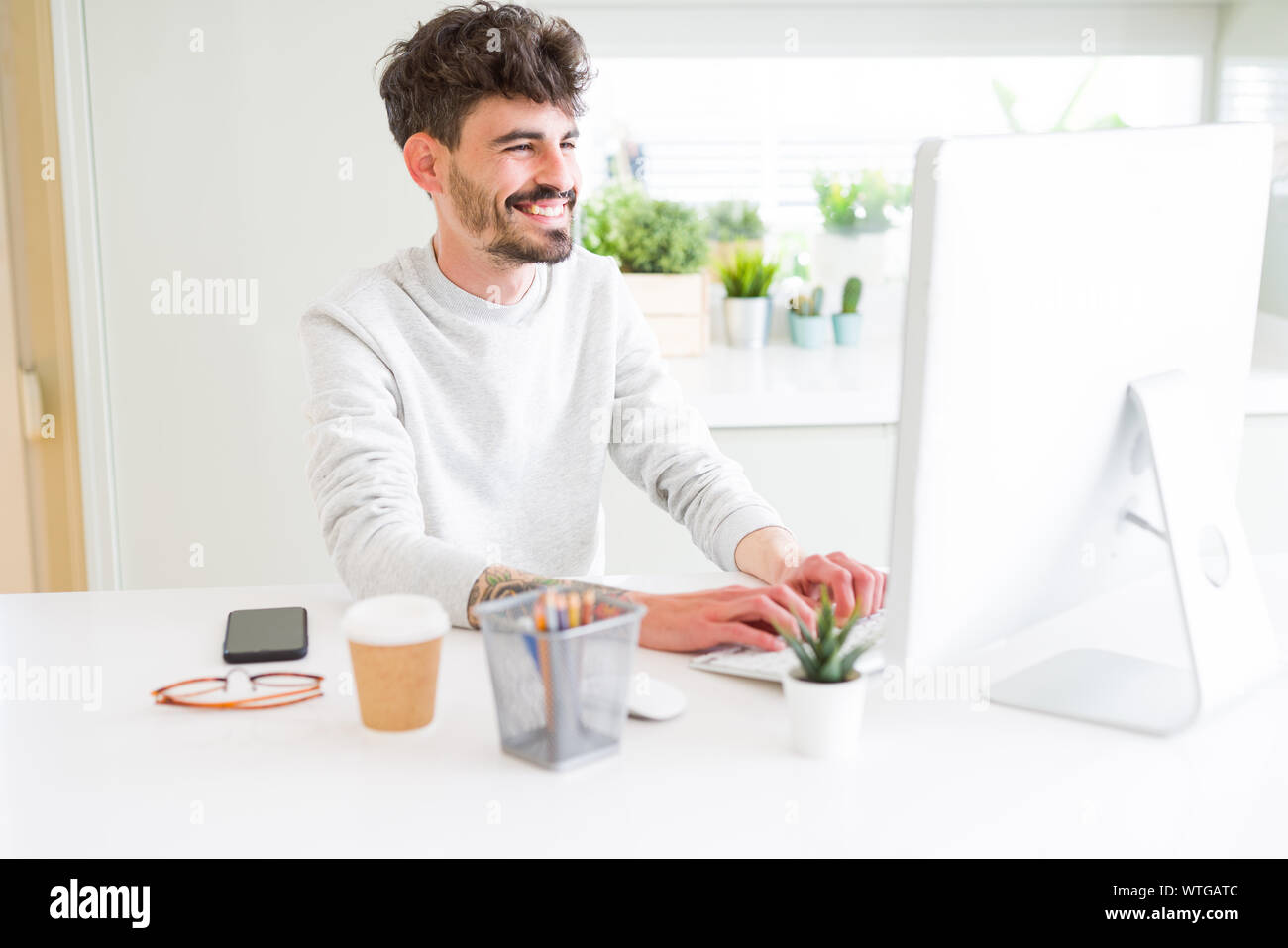 Young handsome man working using computer, smiling concentrated on ...