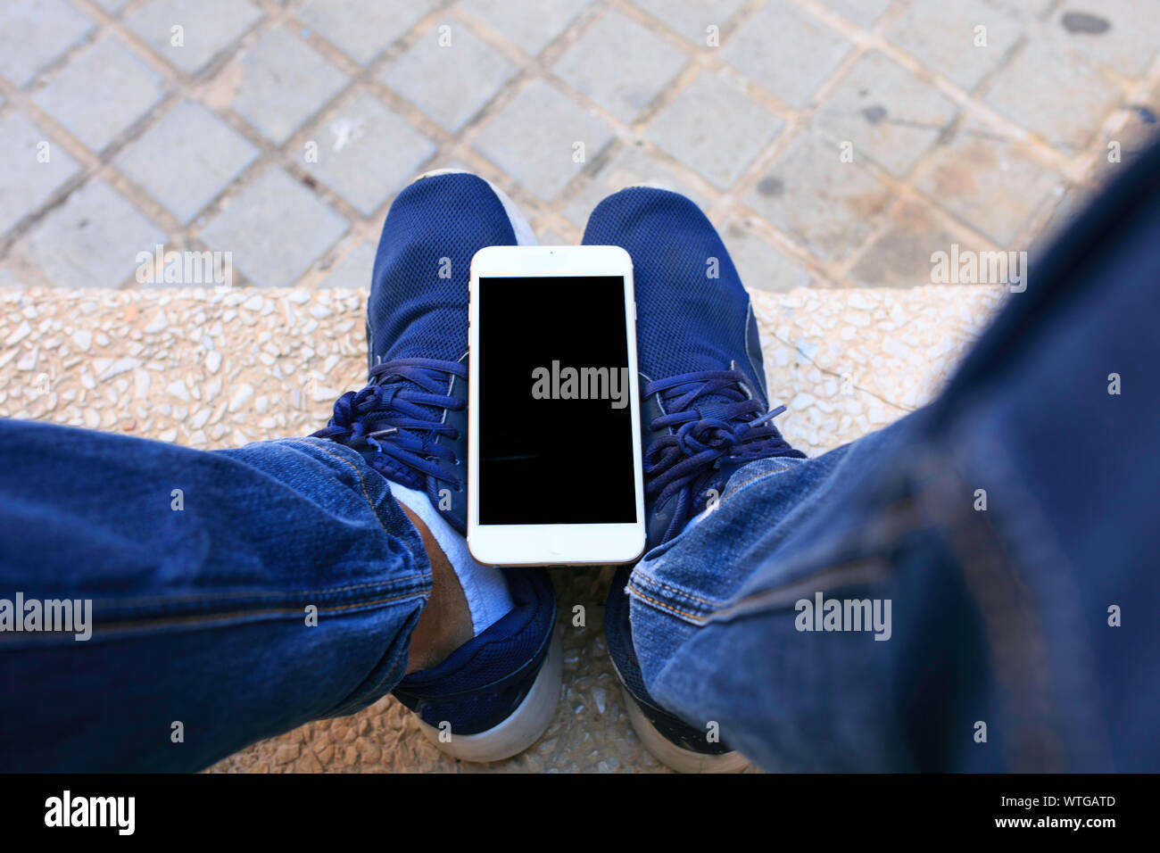 Man holding his telephone in their legs Stock Photo - Alamy