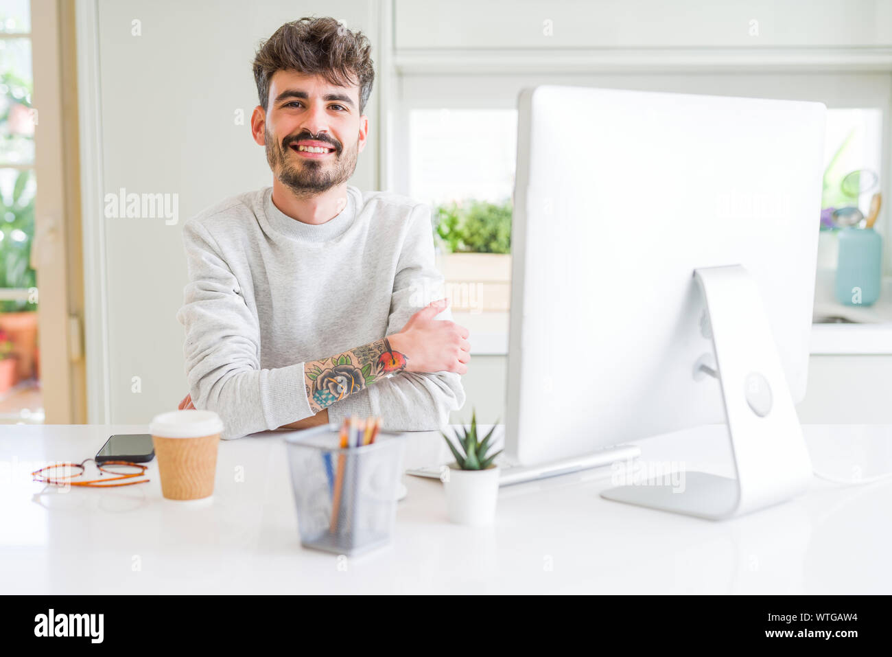 Young man working using computer happy face smiling with crossed arms ...
