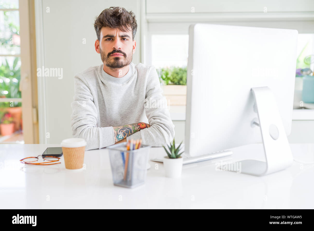Young man working using computer skeptic and nervous, disapproving ...