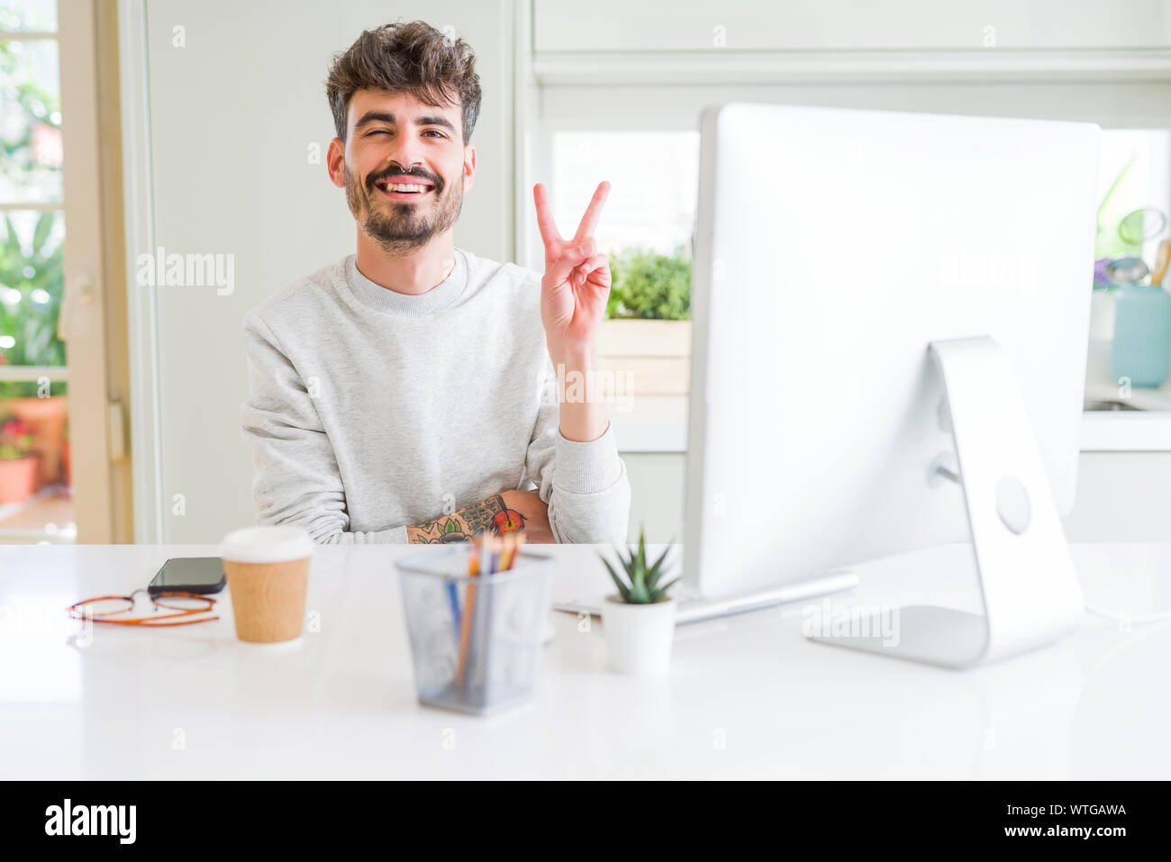 Young man working using computer smiling with happy face winking at the ...