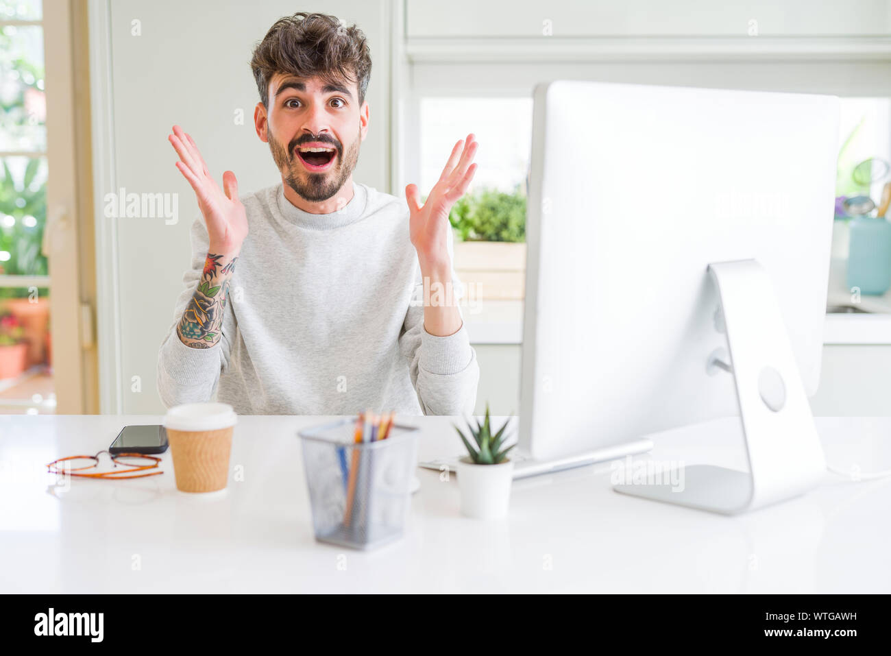 Young man working using computer celebrating crazy and amazed for ...