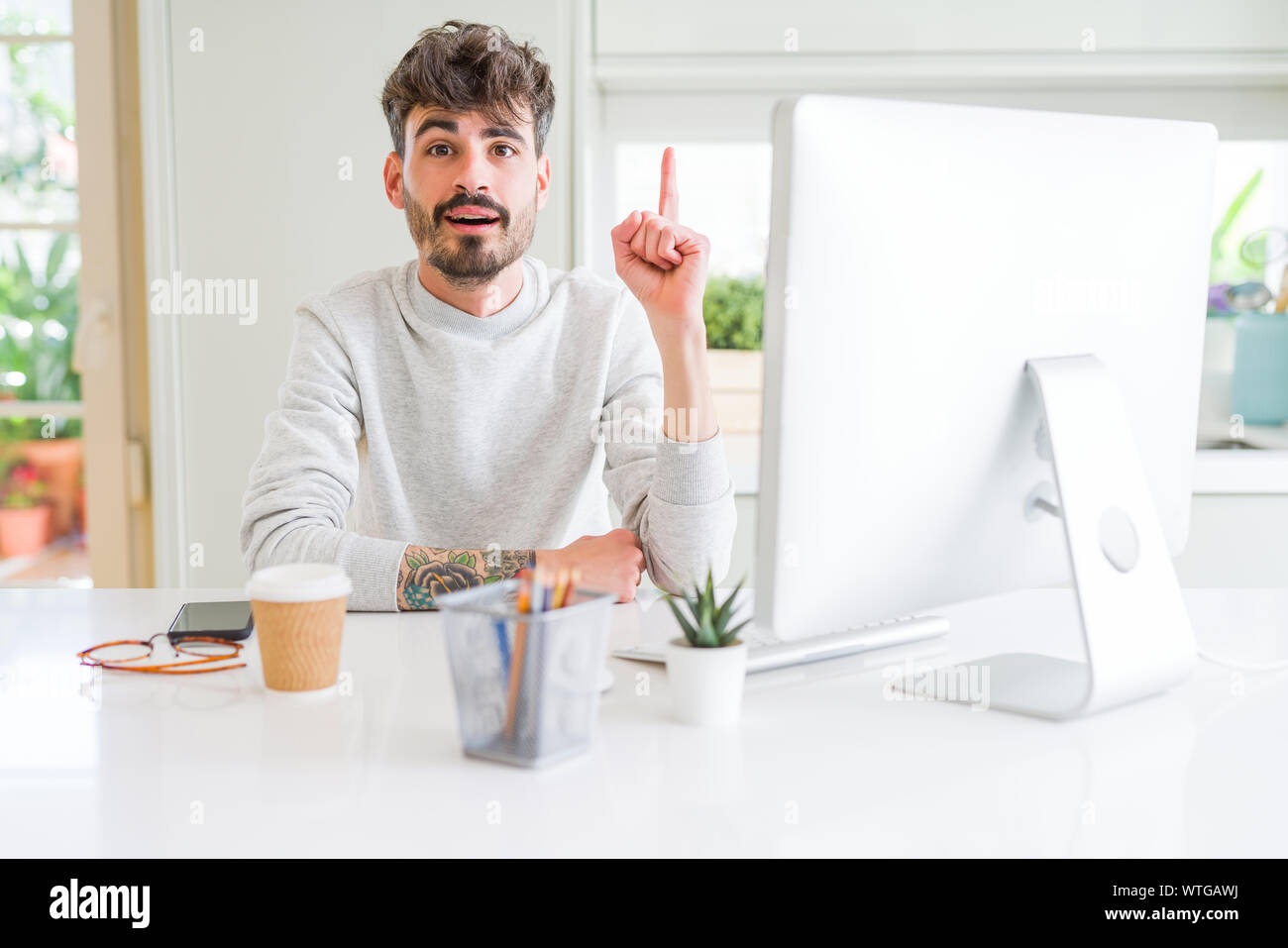 Young man working using computer pointing finger up with successful ...