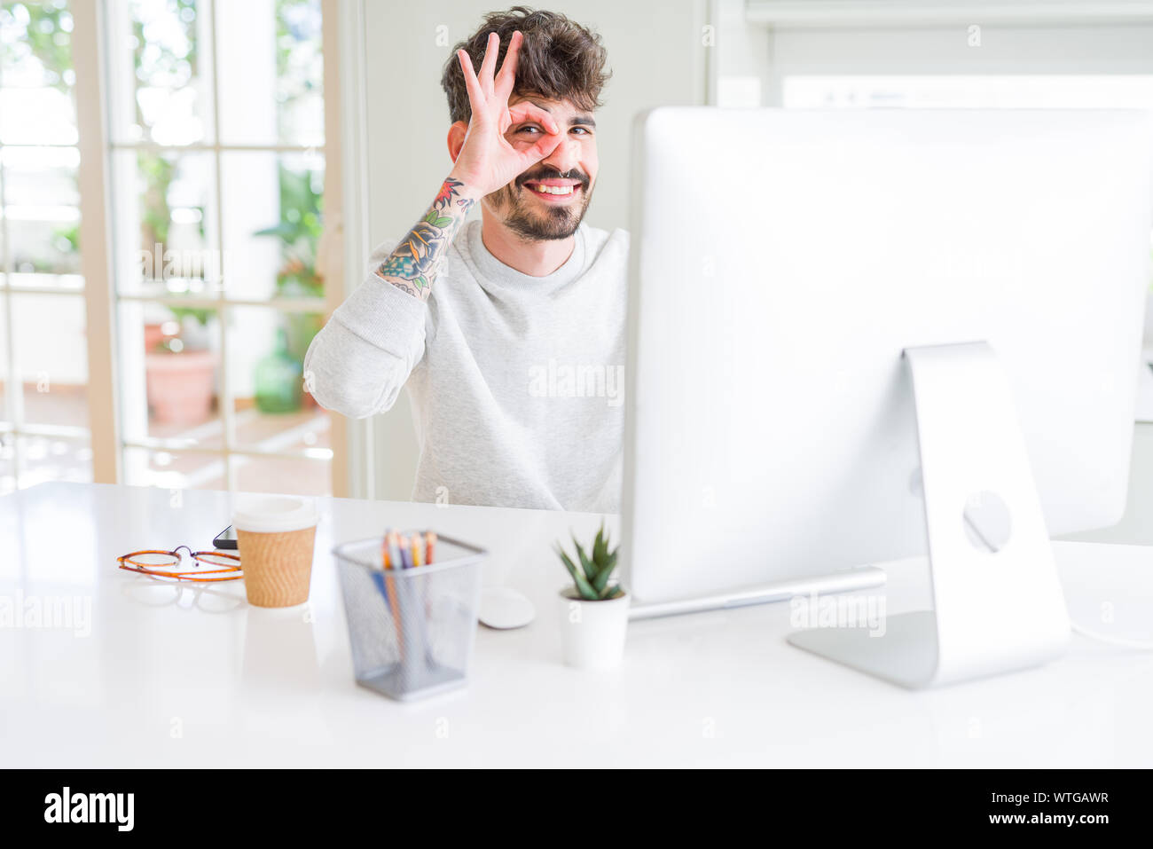 Young man working using computer with happy face smiling doing ok sign ...
