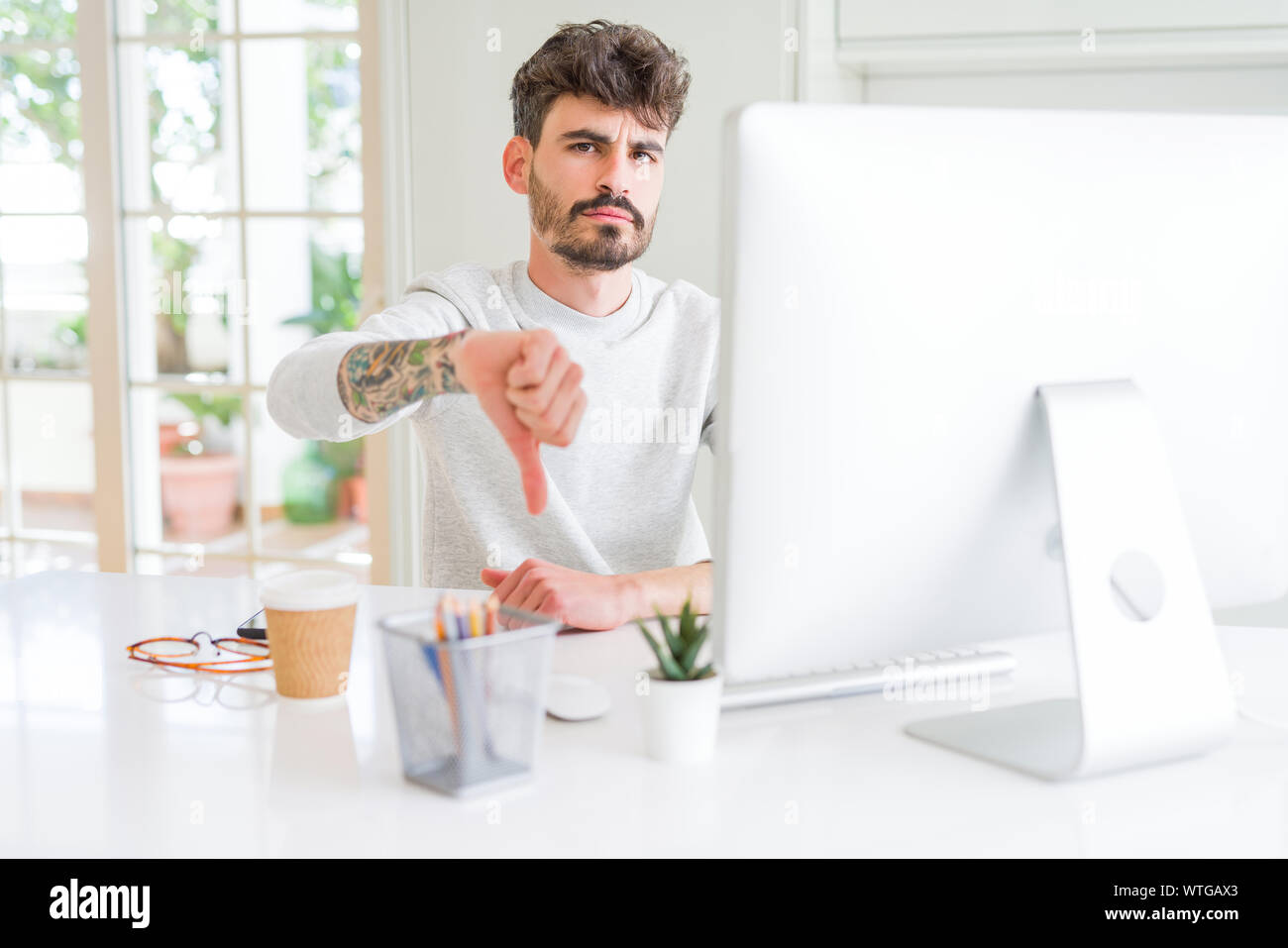 Young man working using computer with angry face, negative sign showing ...