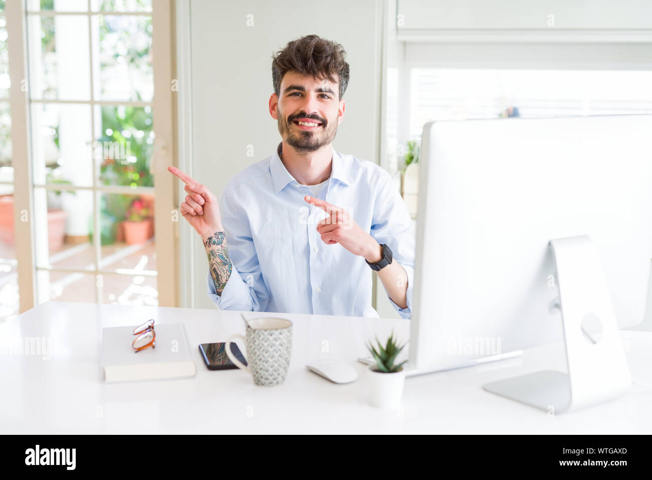 Young business man working using computer smiling and looking at the ...