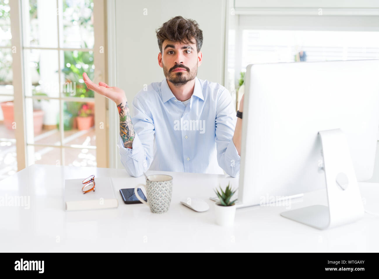 Young business man working using computer clueless and confused ...