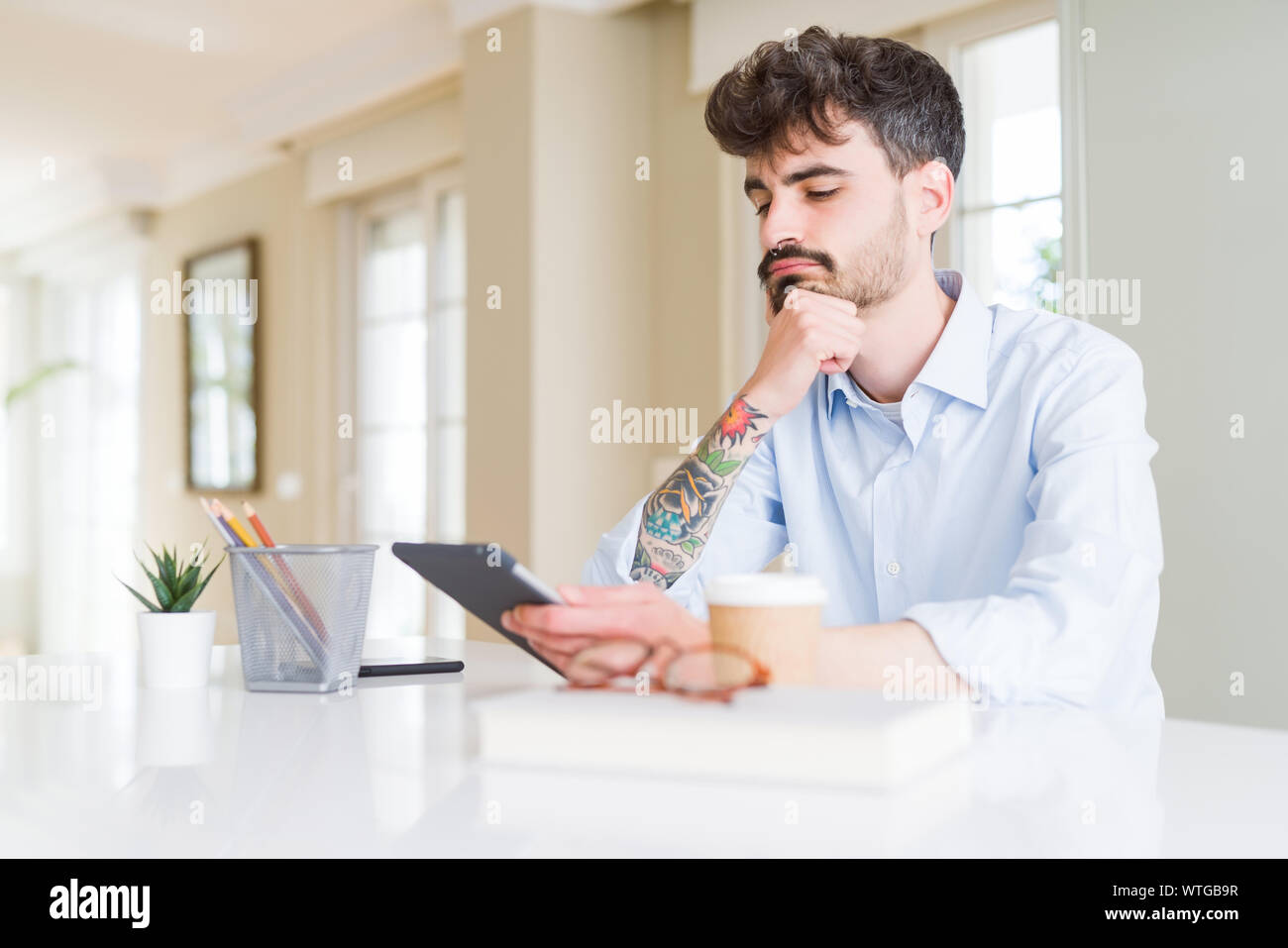 Young business man using touchpad tablet serious face thinking about ...