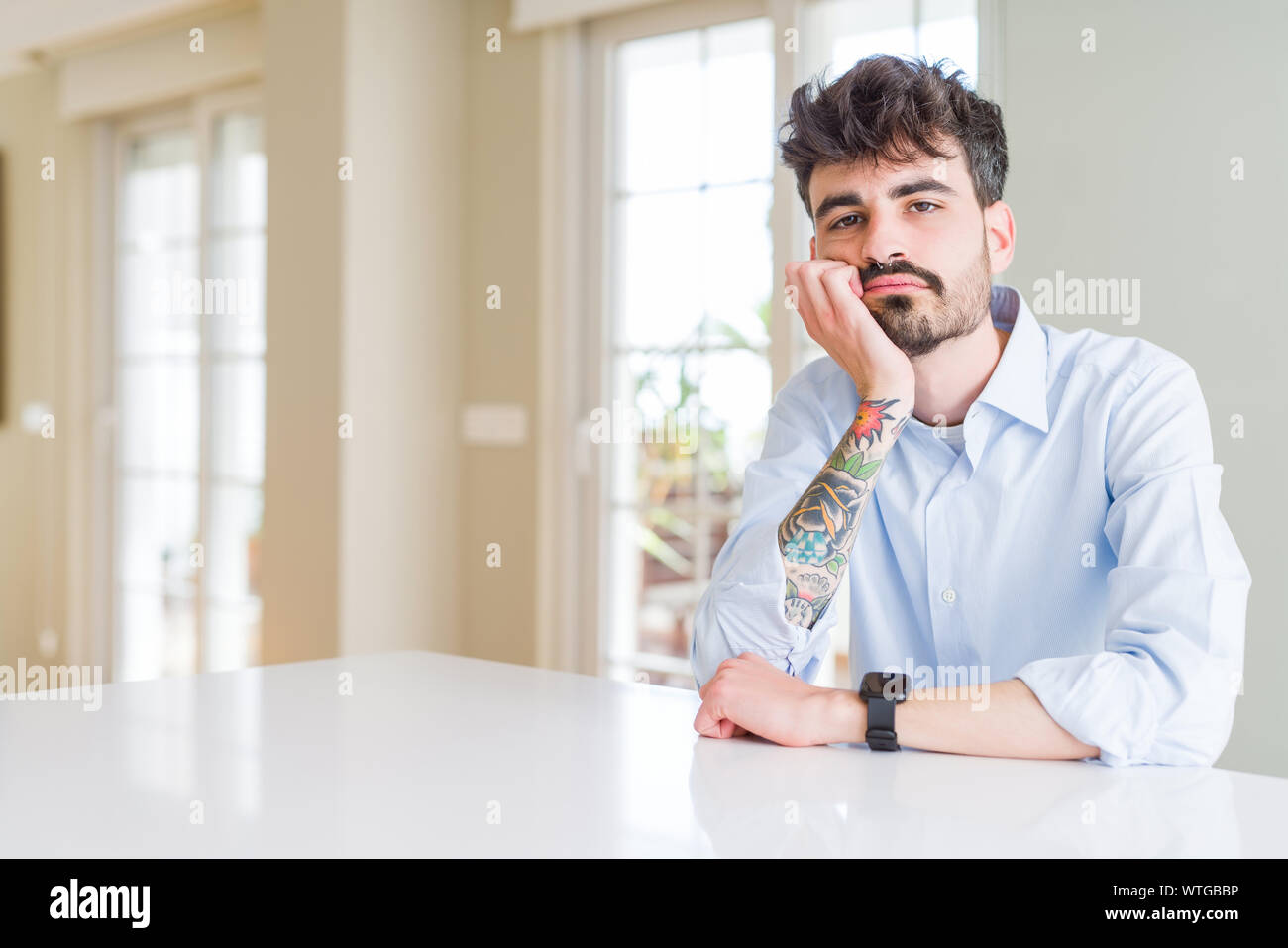 Young businesss man sitting on white table thinking looking tired and ...