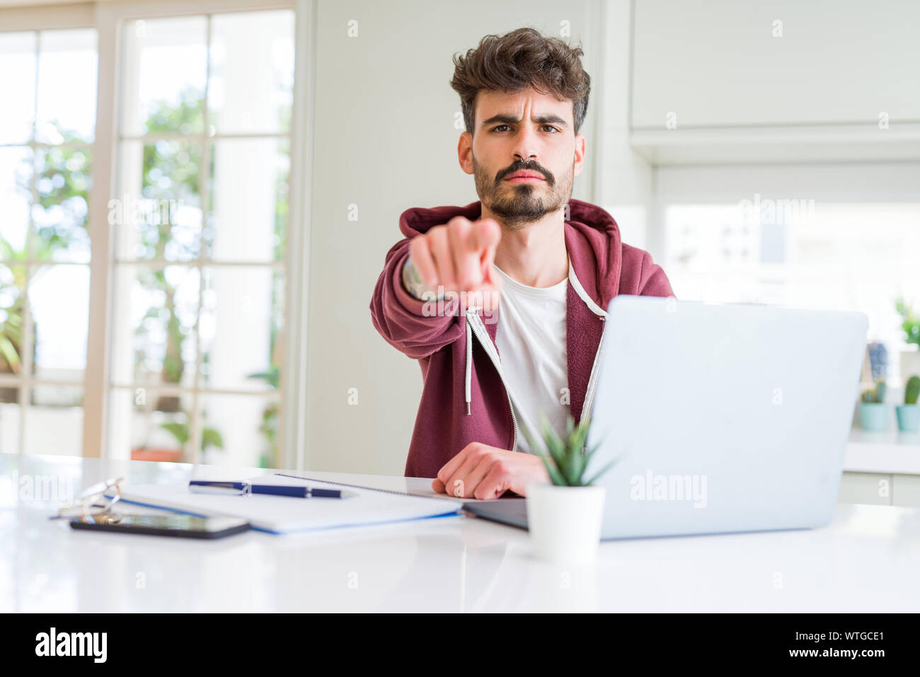 Young student man using computer laptop and notebook pointing with ...