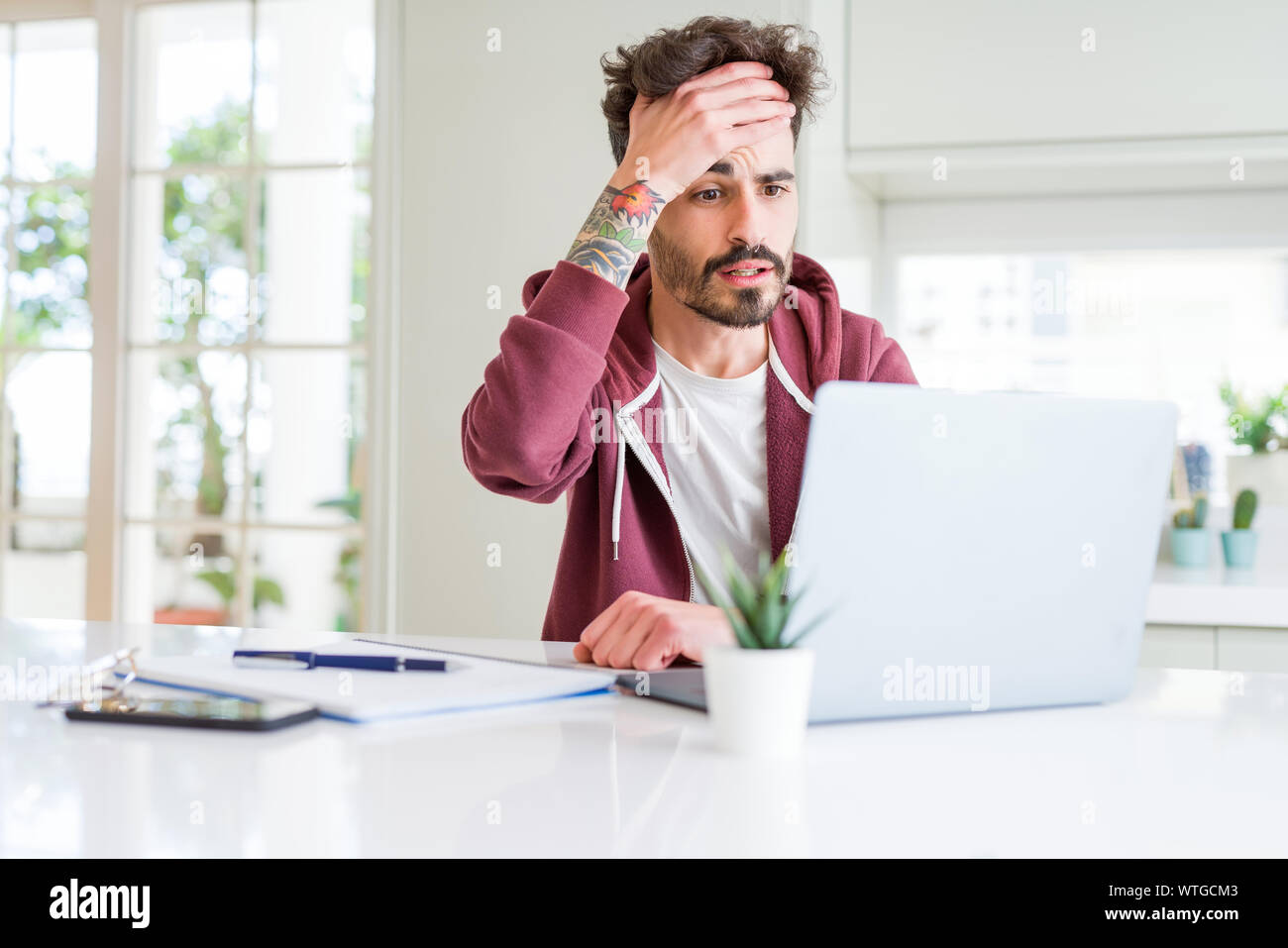 Young student man using computer laptop and notebook stressed with hand ...