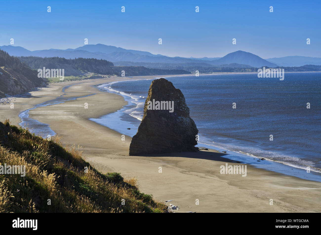 The beach at Cape Blanco State Park, lined by cliffs and sea stacks ...