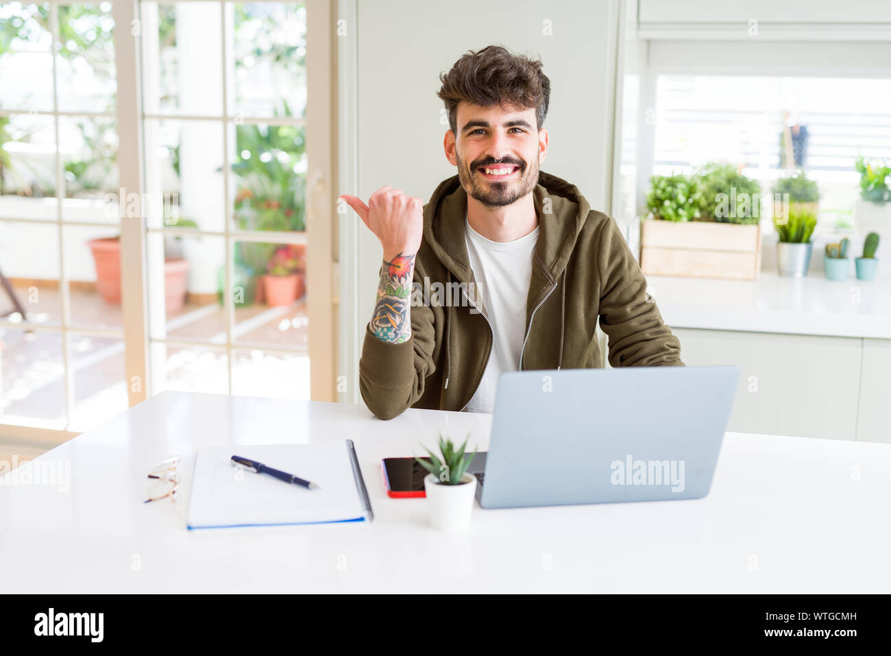 Young student man using computer laptop and notebook pointing and ...
