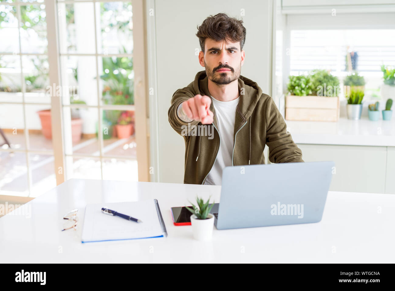 Young student man using computer laptop and notebook pointing with ...