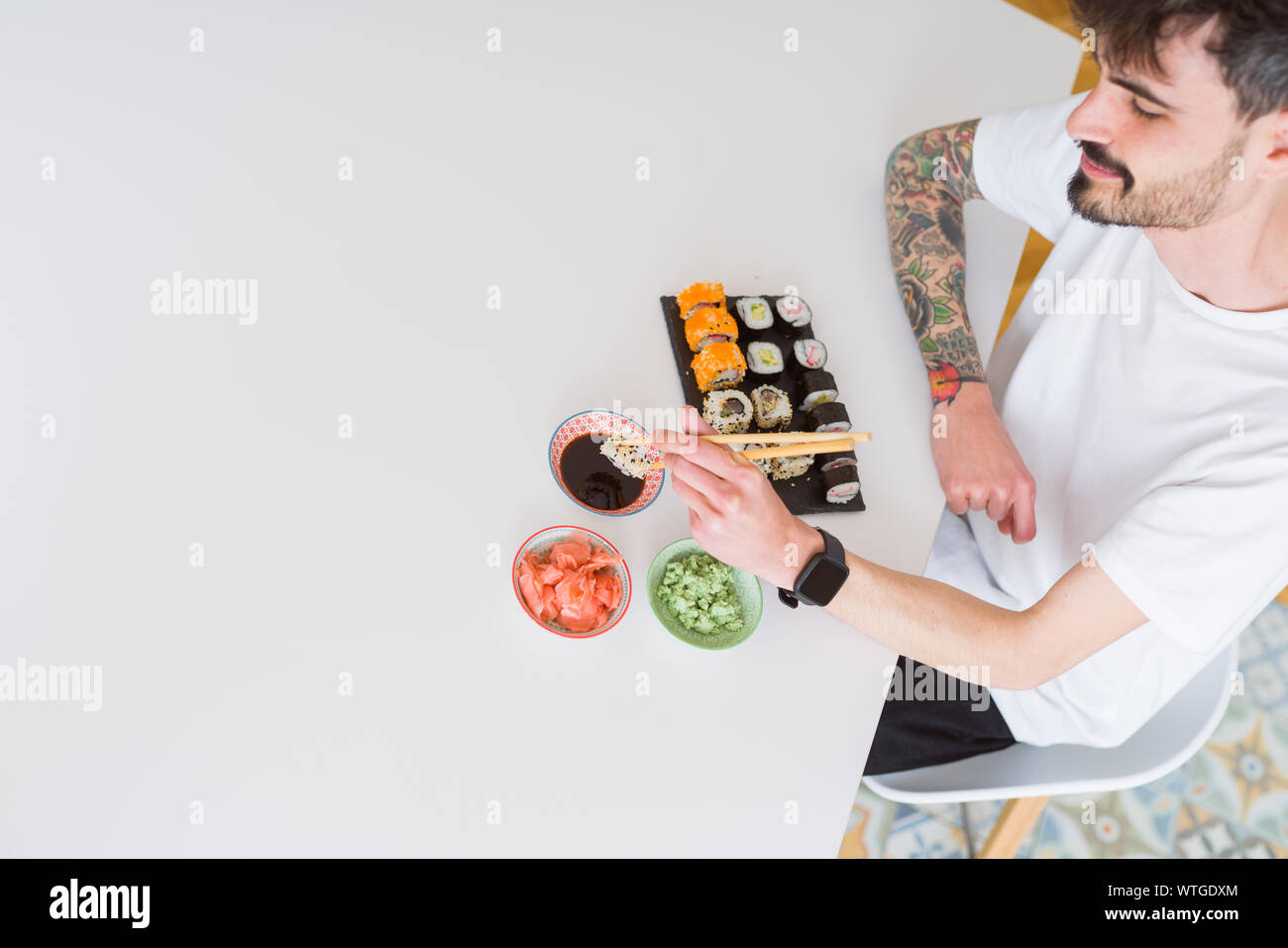 Overhead angle of young man eating sushi asian food using choopsticks ...