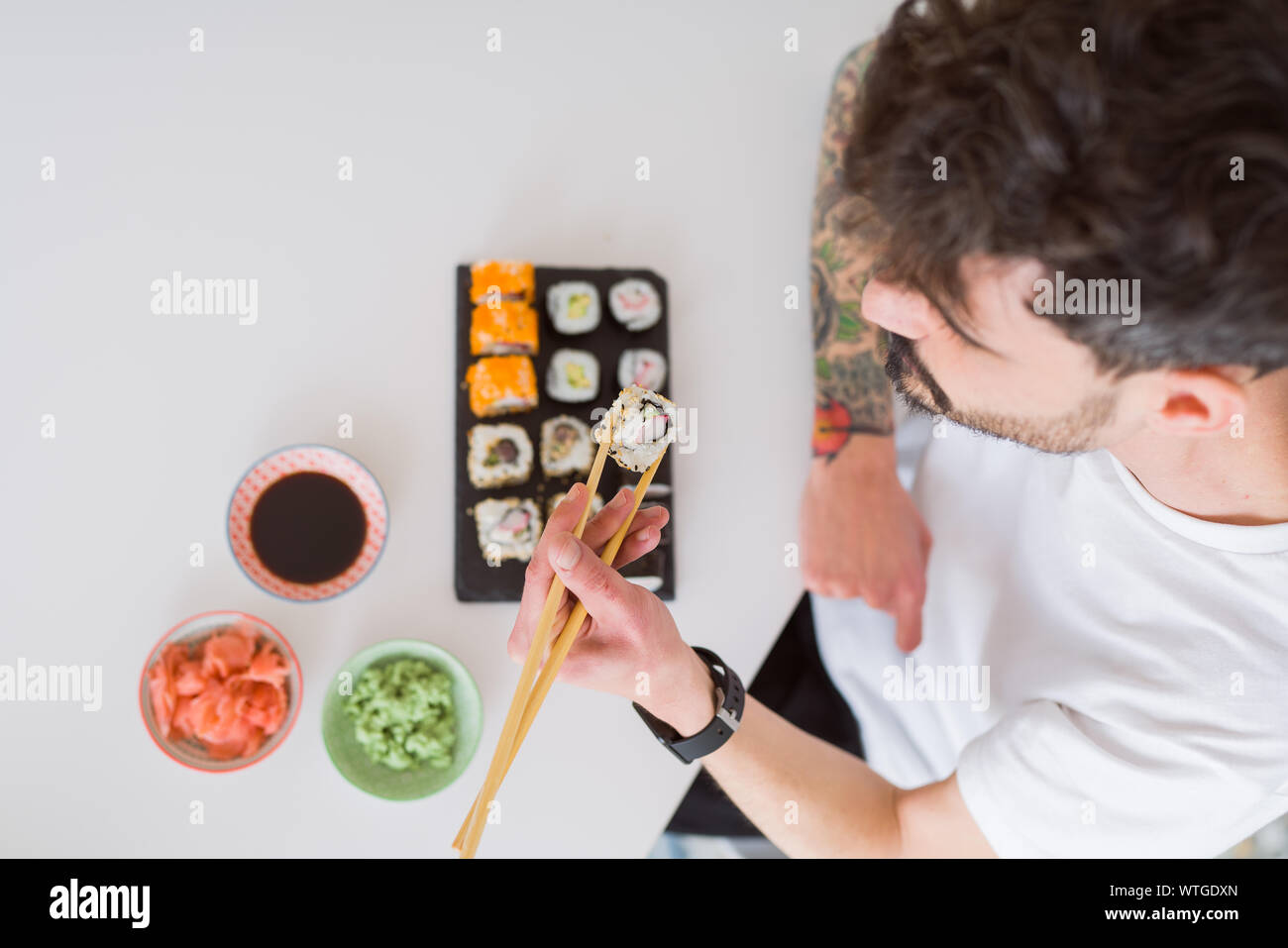 Overhead angle of young man eating sushi asian food using choopsticks ...