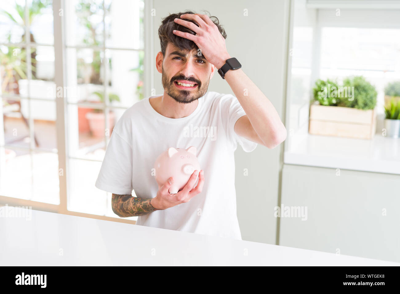 Young man holding piggy bank as insurance investment stressed with hand ...