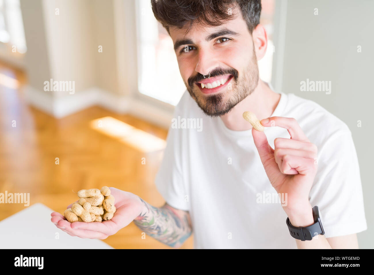 Young man eating peanuts, close up of hand with a bunch of healthy nuts ...